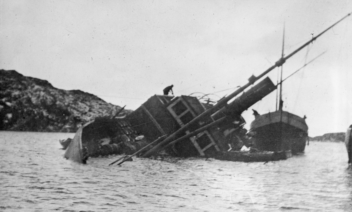 Dampskip med slagside. En mann står oppe på skipets langside. Et fartøy ...